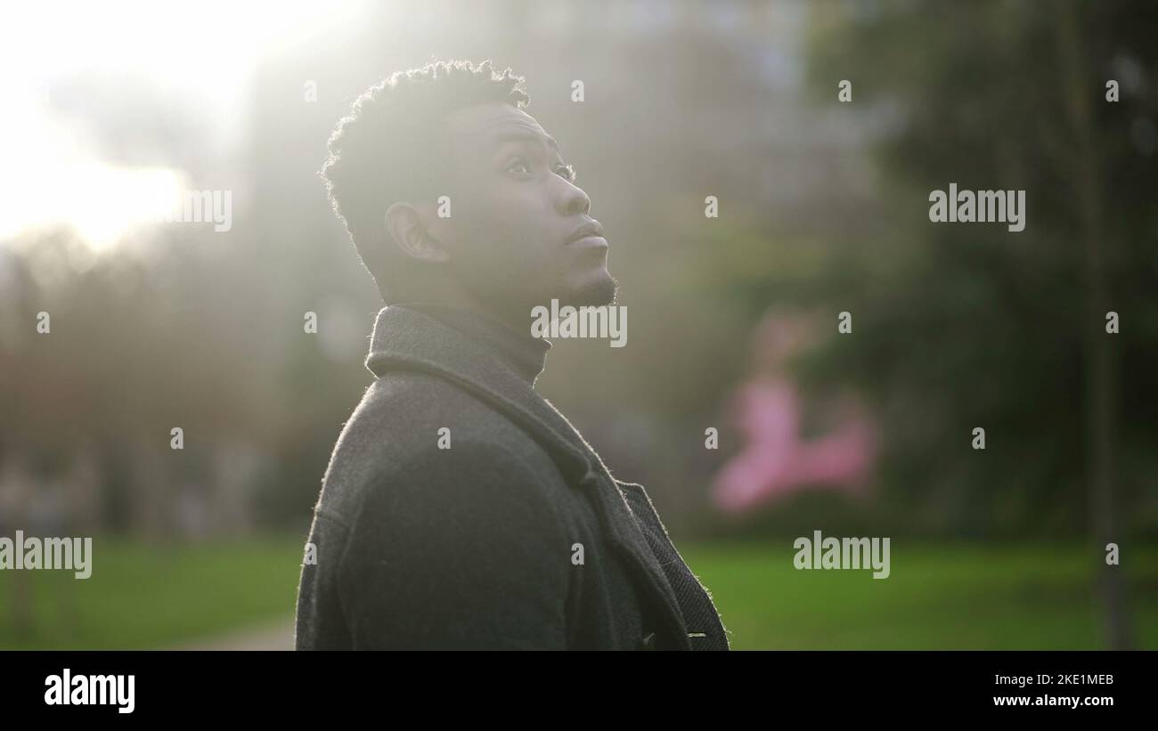 African young black man standing at park looking up in contemplation ...
