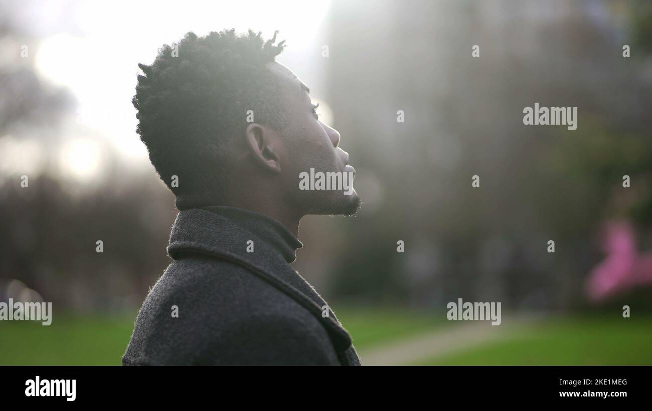 African young black man standing at park looking up in contemplation ...