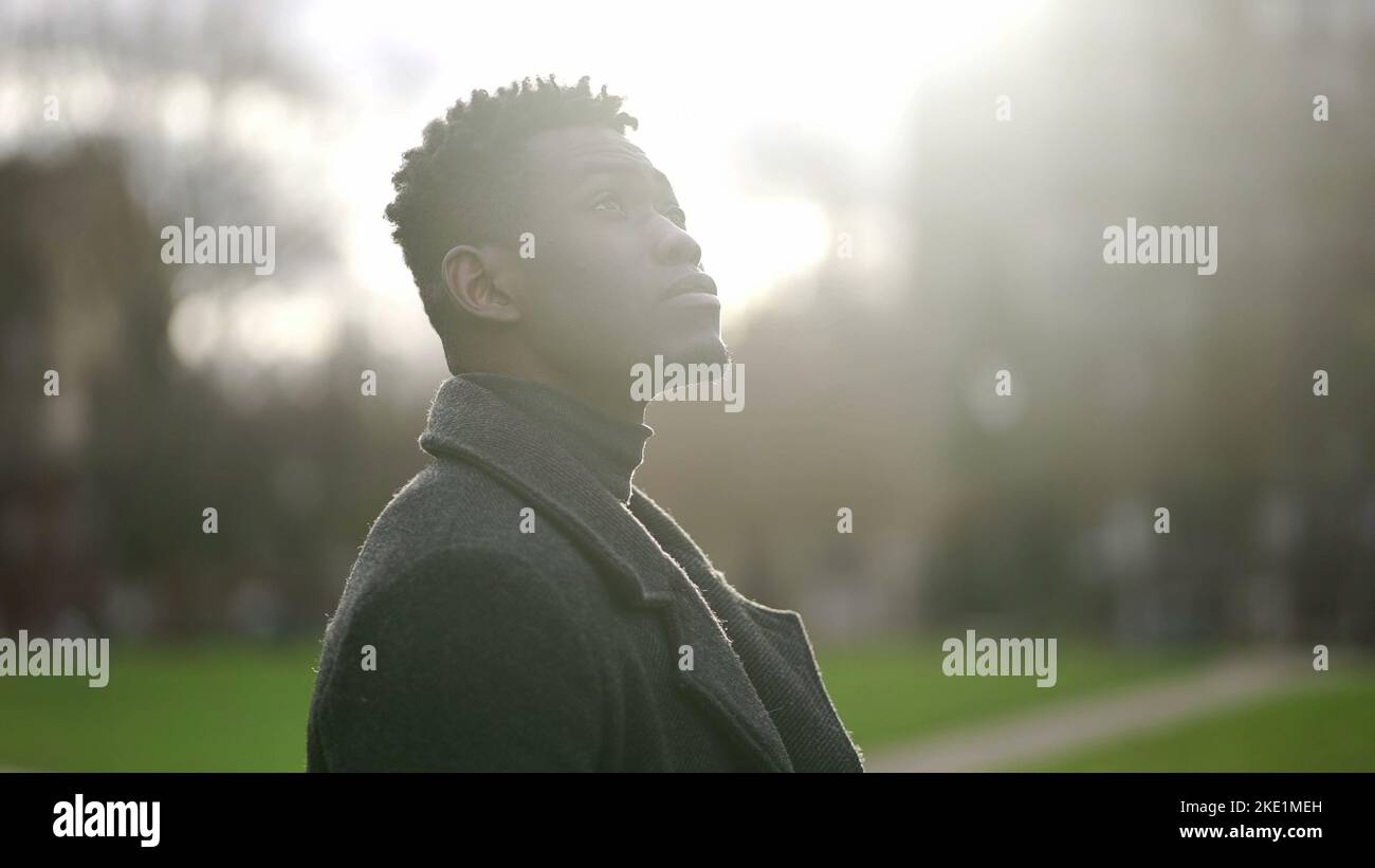 African young black man standing at park looking up in contemplation ...