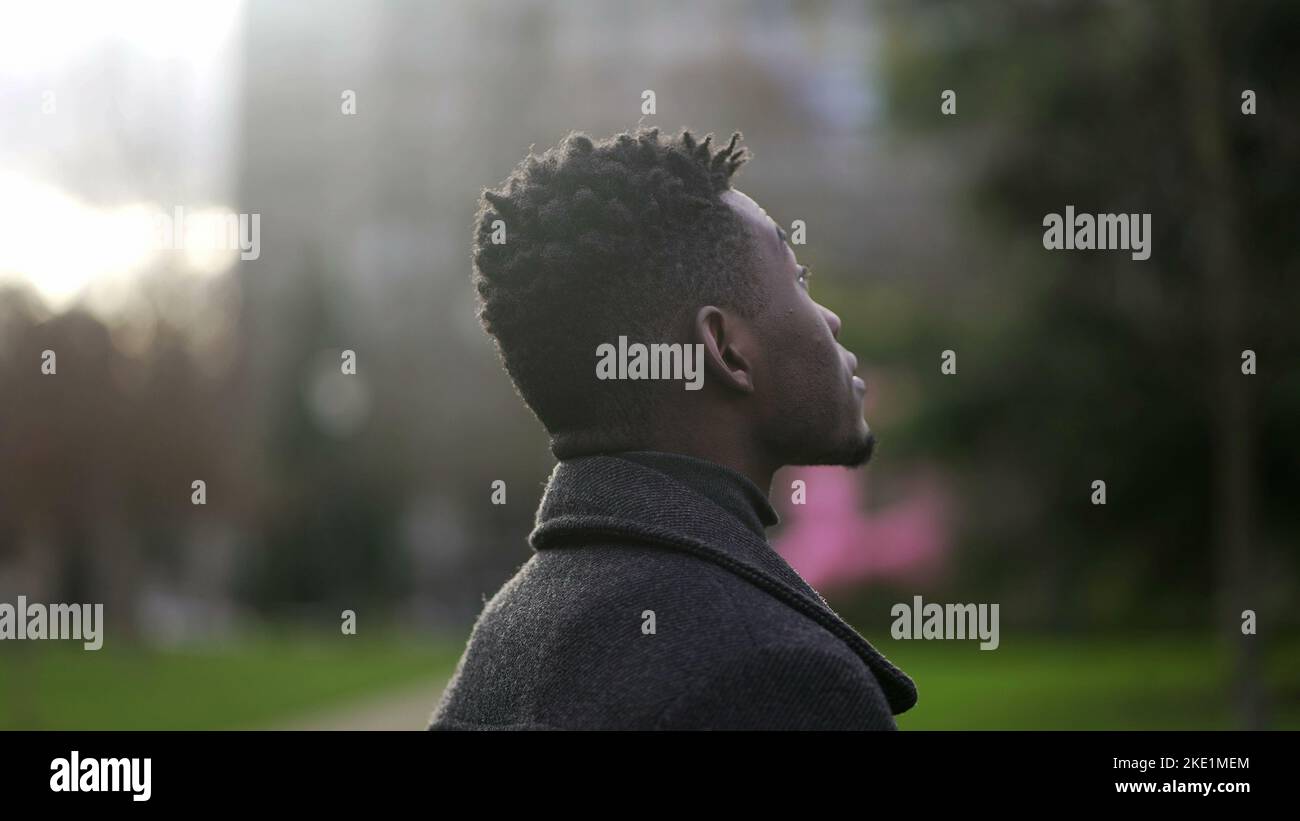 African young black man standing at park looking up in contemplation ...