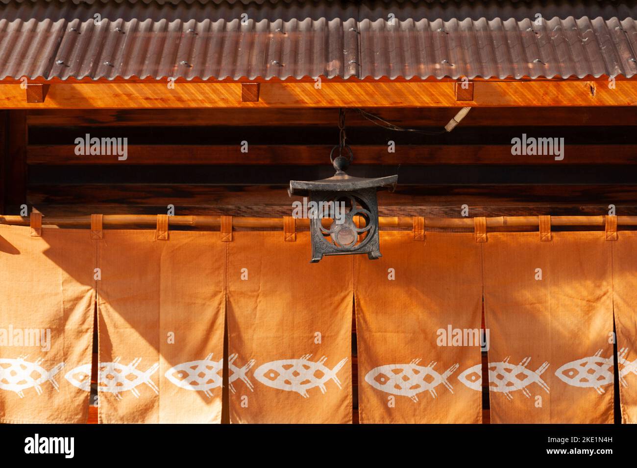 A traditional lantern and orange noren curtain (with a design of fish ...