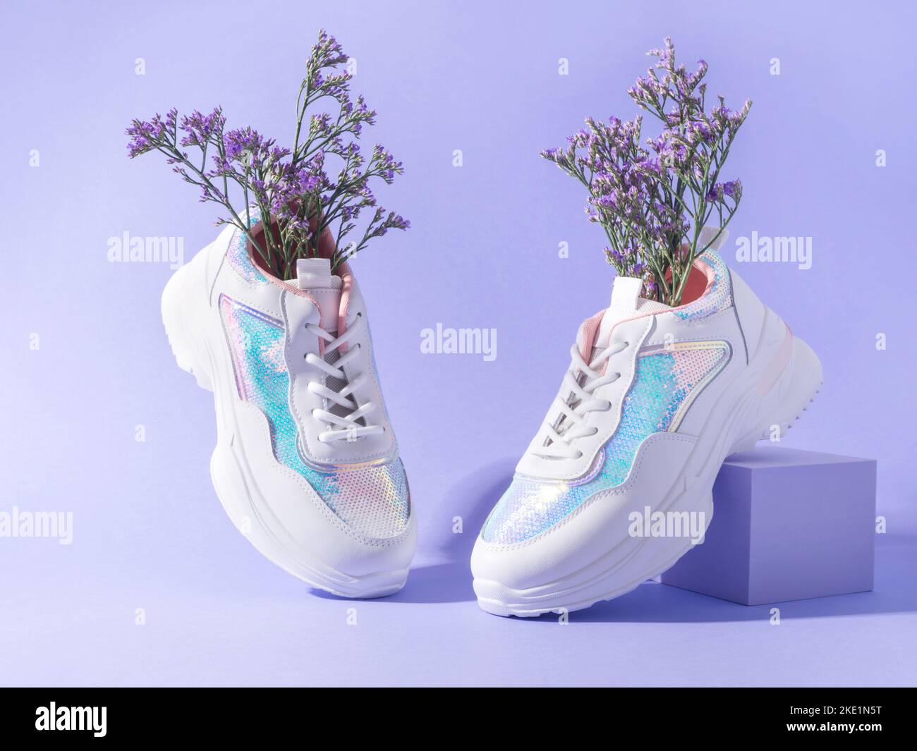 White sneakers with sequins with flowers on purple geometric background ...