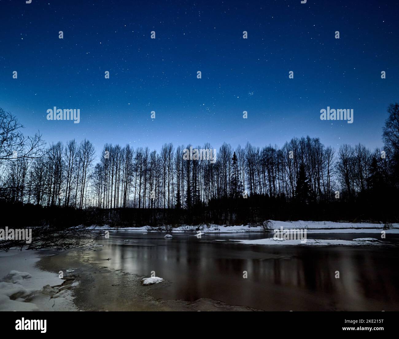 A small lake at night with a blue starry sky in the background, perfect ...