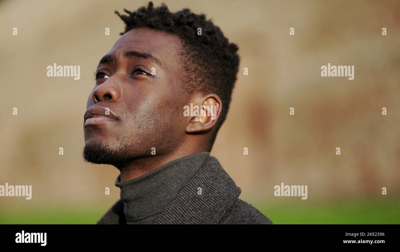 African young black man standing at park looking up in contemplation2 ...