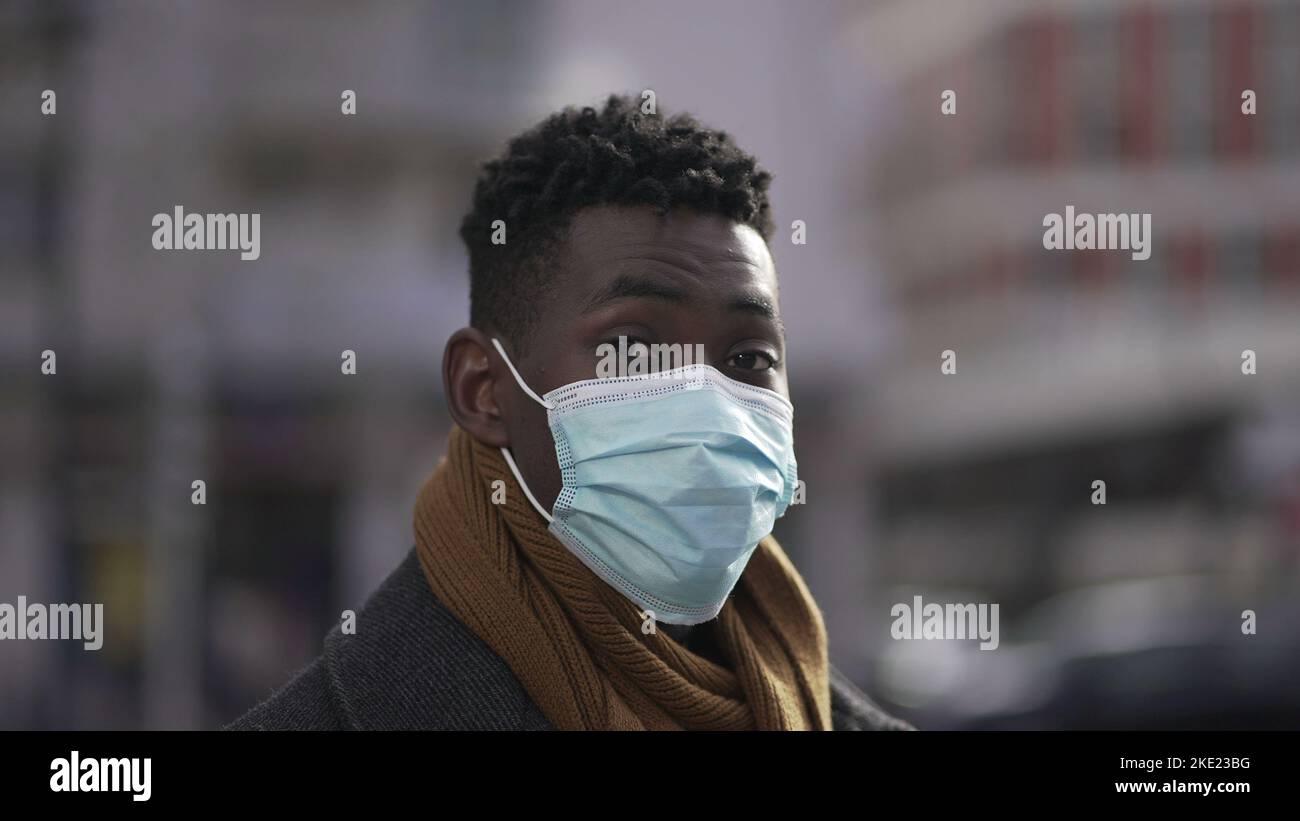 Black African man wearing covid-19 surgical face mask standing outside ...