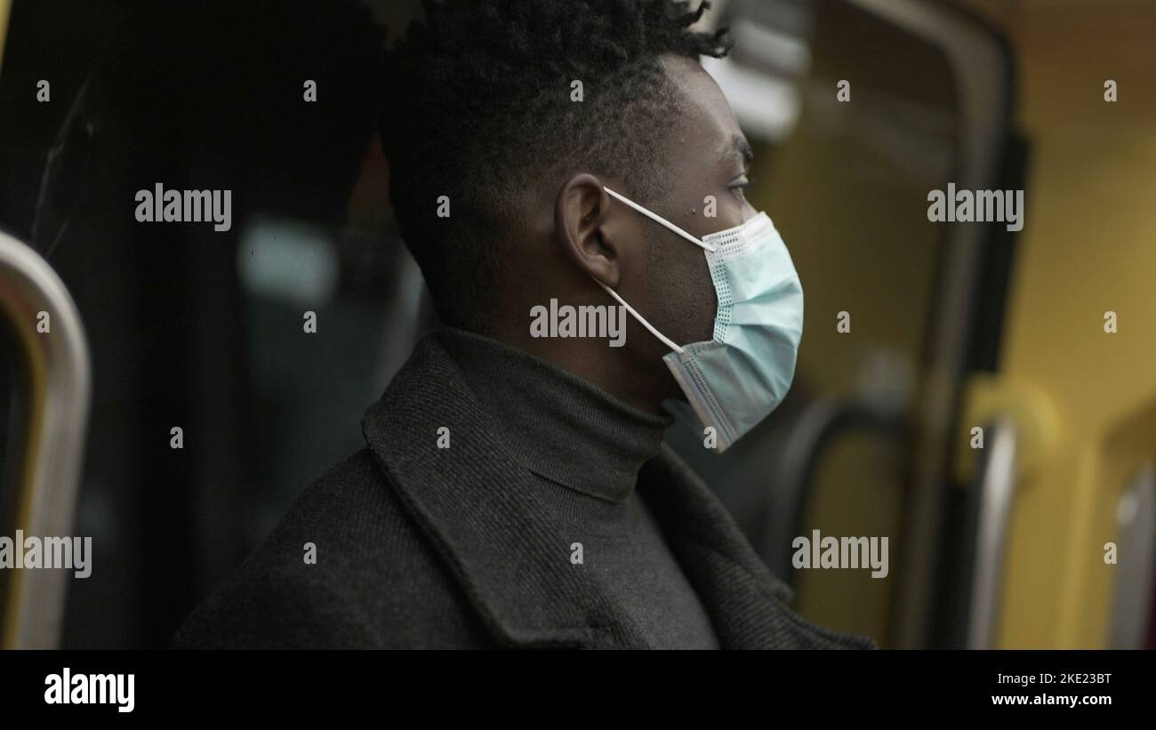 Black man adjusting face mask riding train metro. Person commuting ...
