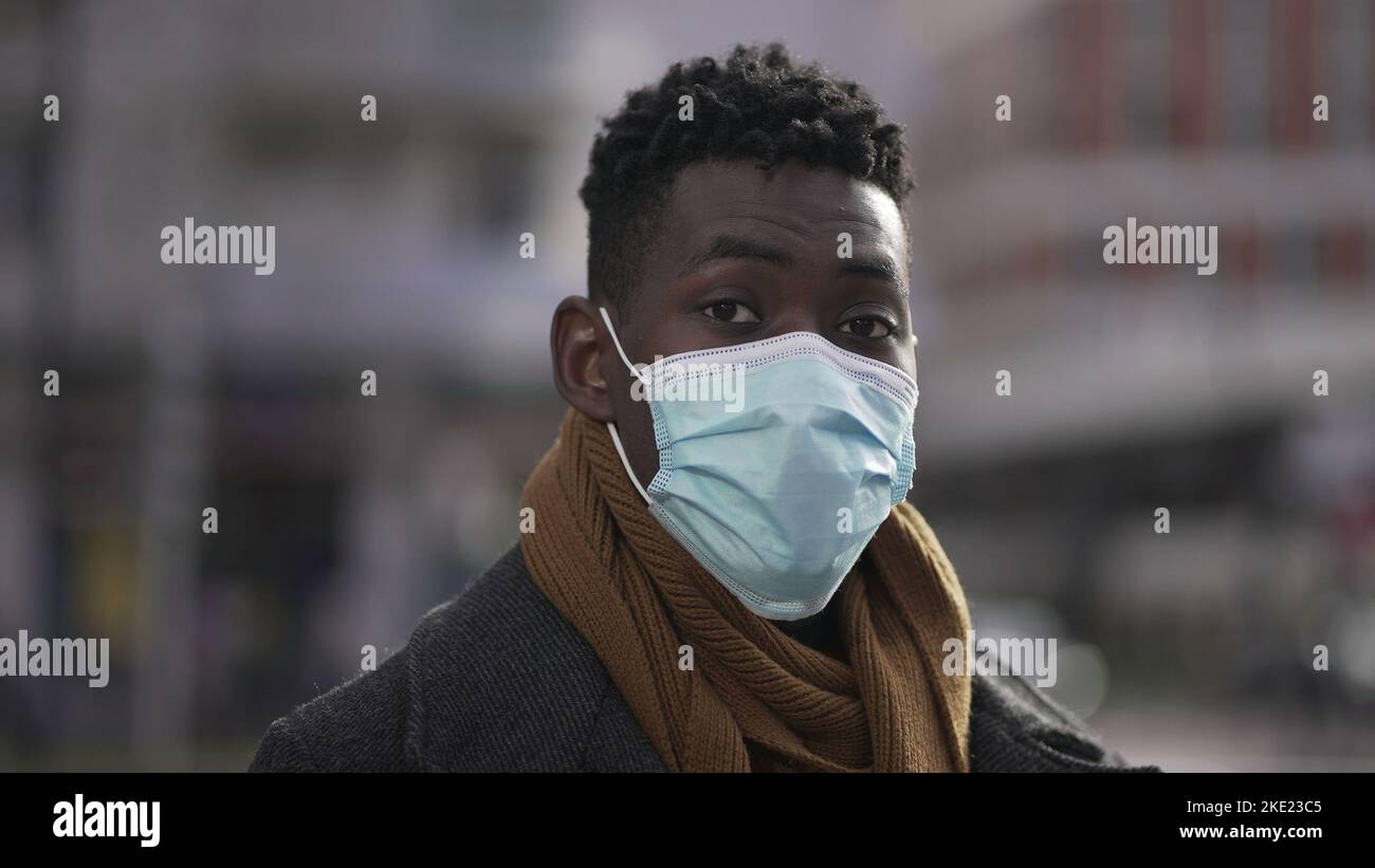 Black African man wearing covid-19 surgical face mask standing outside ...