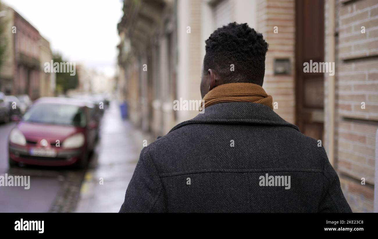 Back of black walking outside in city sidewalk downtown. African person ...
