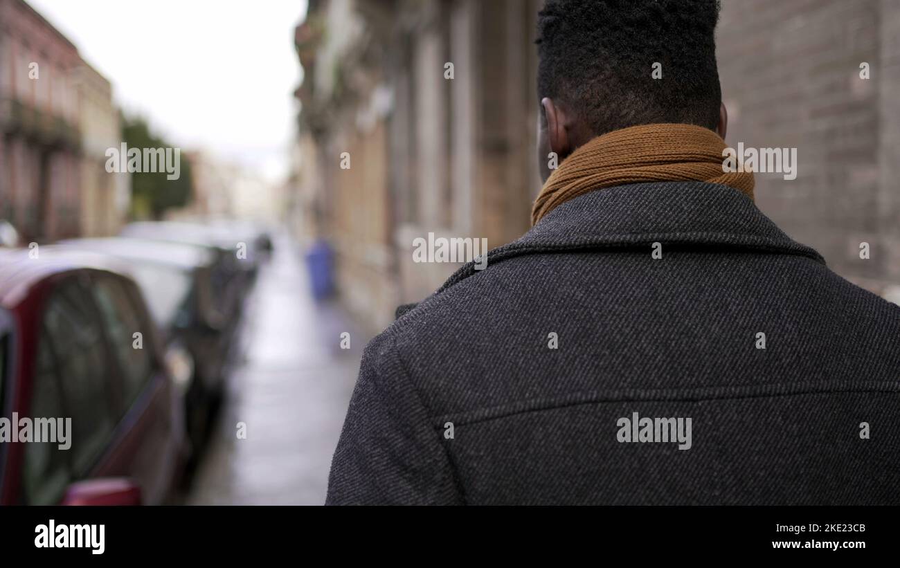 Back of black walking outside in city sidewalk downtown. African person ...