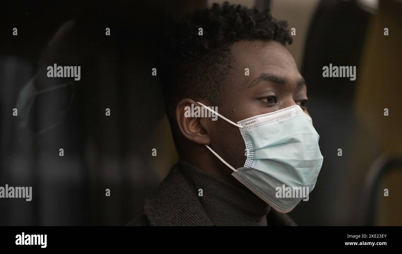 Black man adjusting face mask riding train metro. Person commuting ...