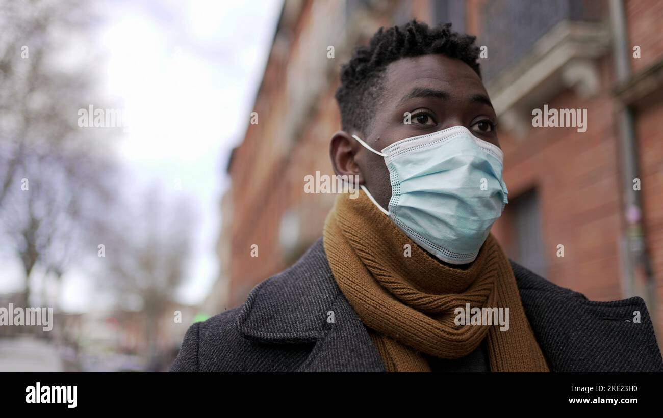 Black African man walking wearing covid surgical face mask in city ...