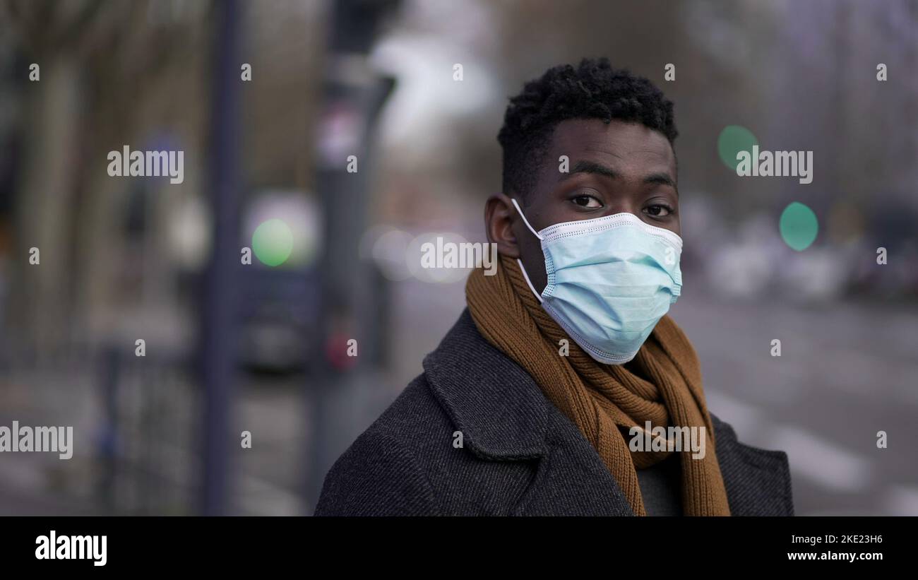 Black African man wearing covid-19 face mask standing outside in street ...