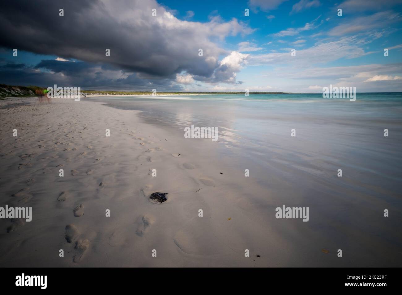 Cloudy sky at a lonely Tortuga Bay beach. Ocean waves are washed out in ...