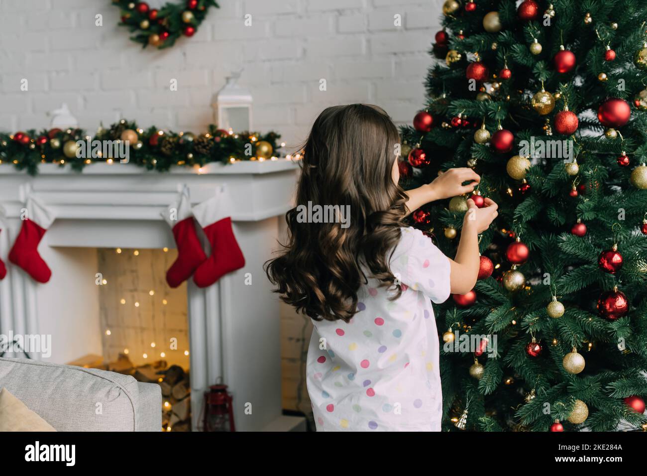 Preteen child in pajama decorating Christmas tree in living room Stock ...