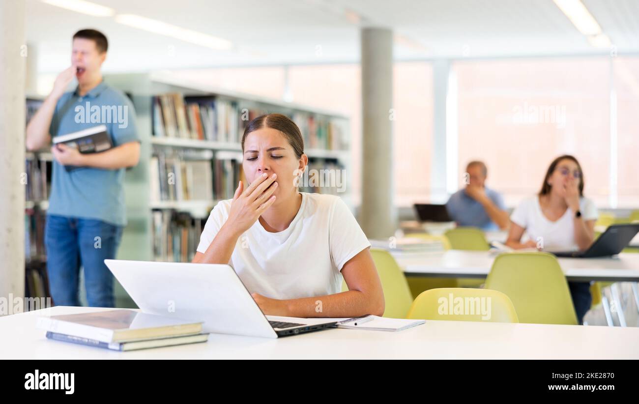 Female student yawns out of boredom in public library Stock Photo - Alamy