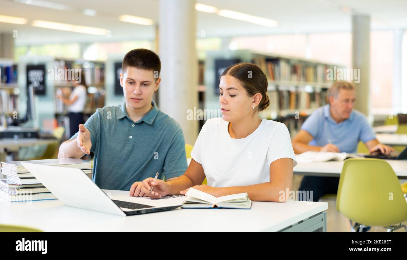 Young interested couple of students spending time together in library ...
