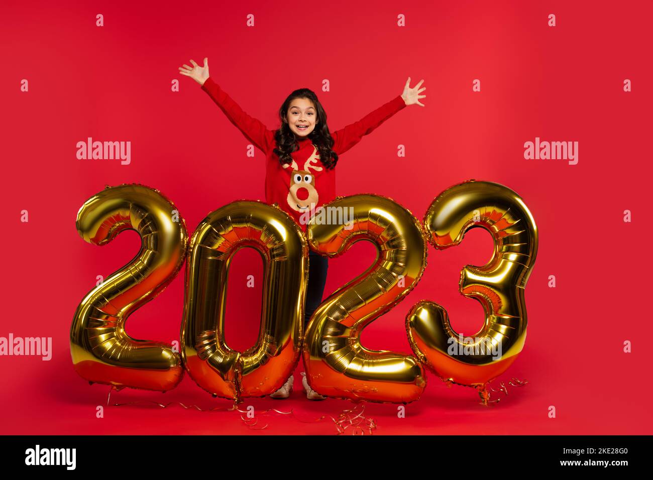 full length of excited girl in sweater standing near balloons with 2023 ...