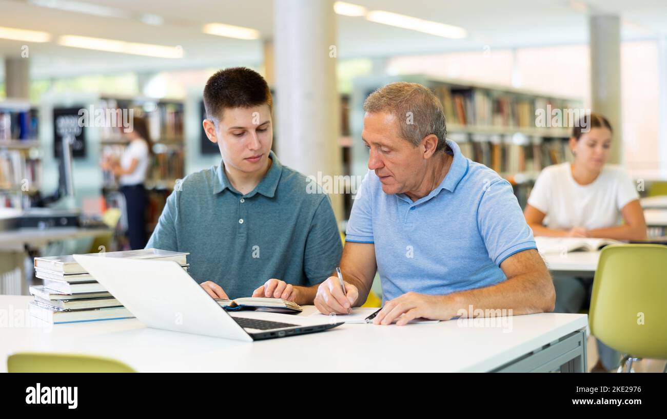 View on a young male student teaching a mature man Stock Photo - Alamy