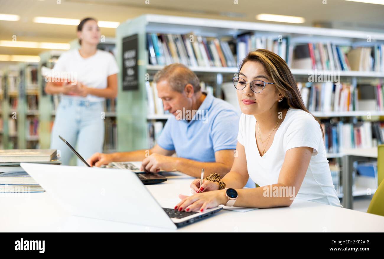 Female Latina college student working on a project with a male elder ...