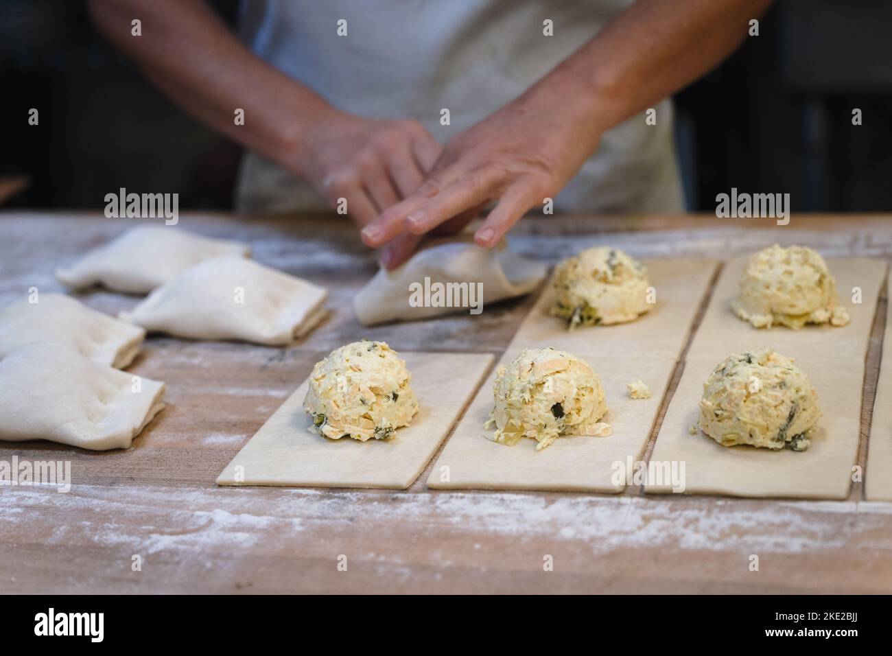 a baker folds pastry dough over a savory filling Stock Photo - Alamy