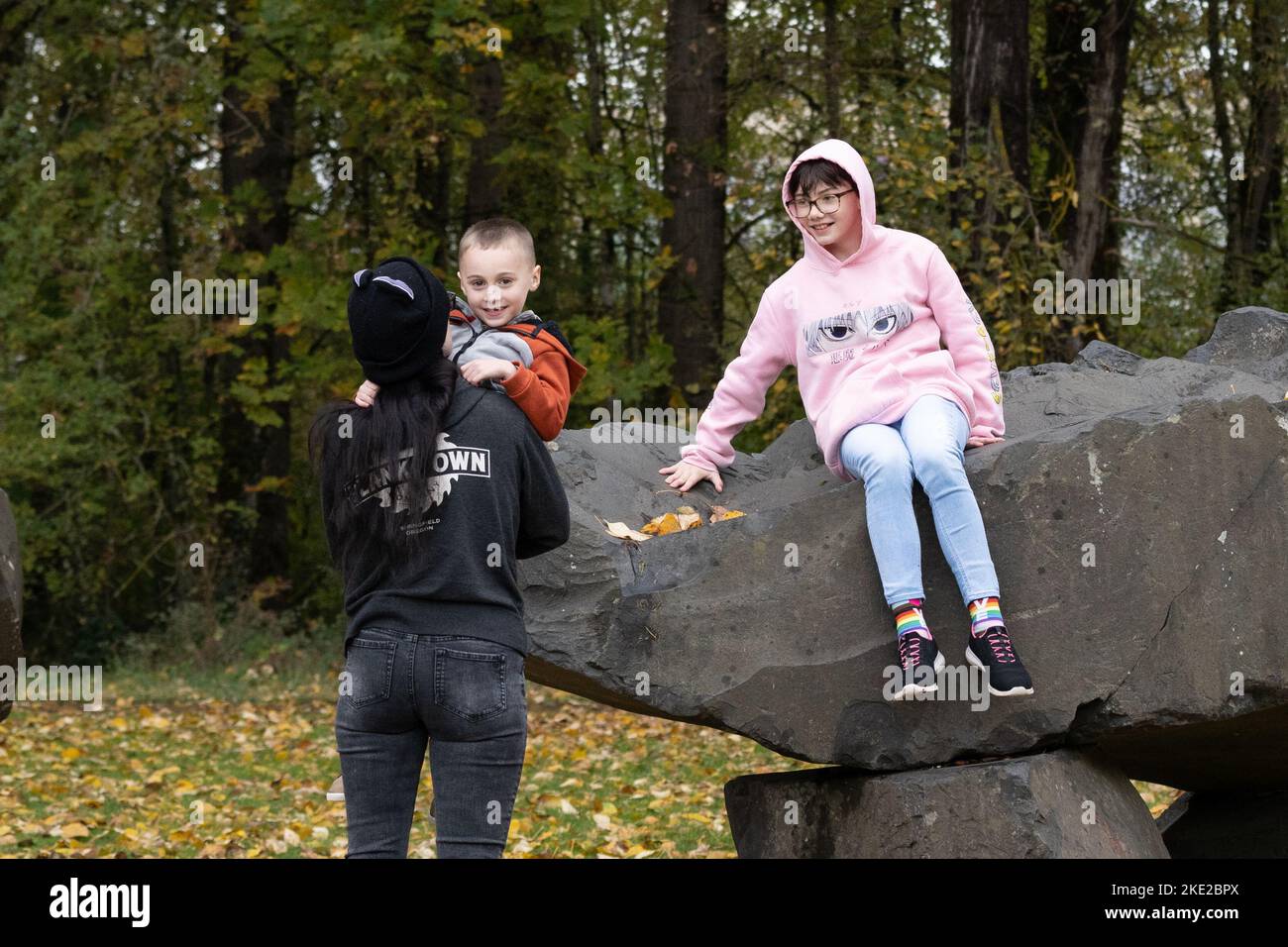A mother and her two children play on the rocks at a park in Autumn ...