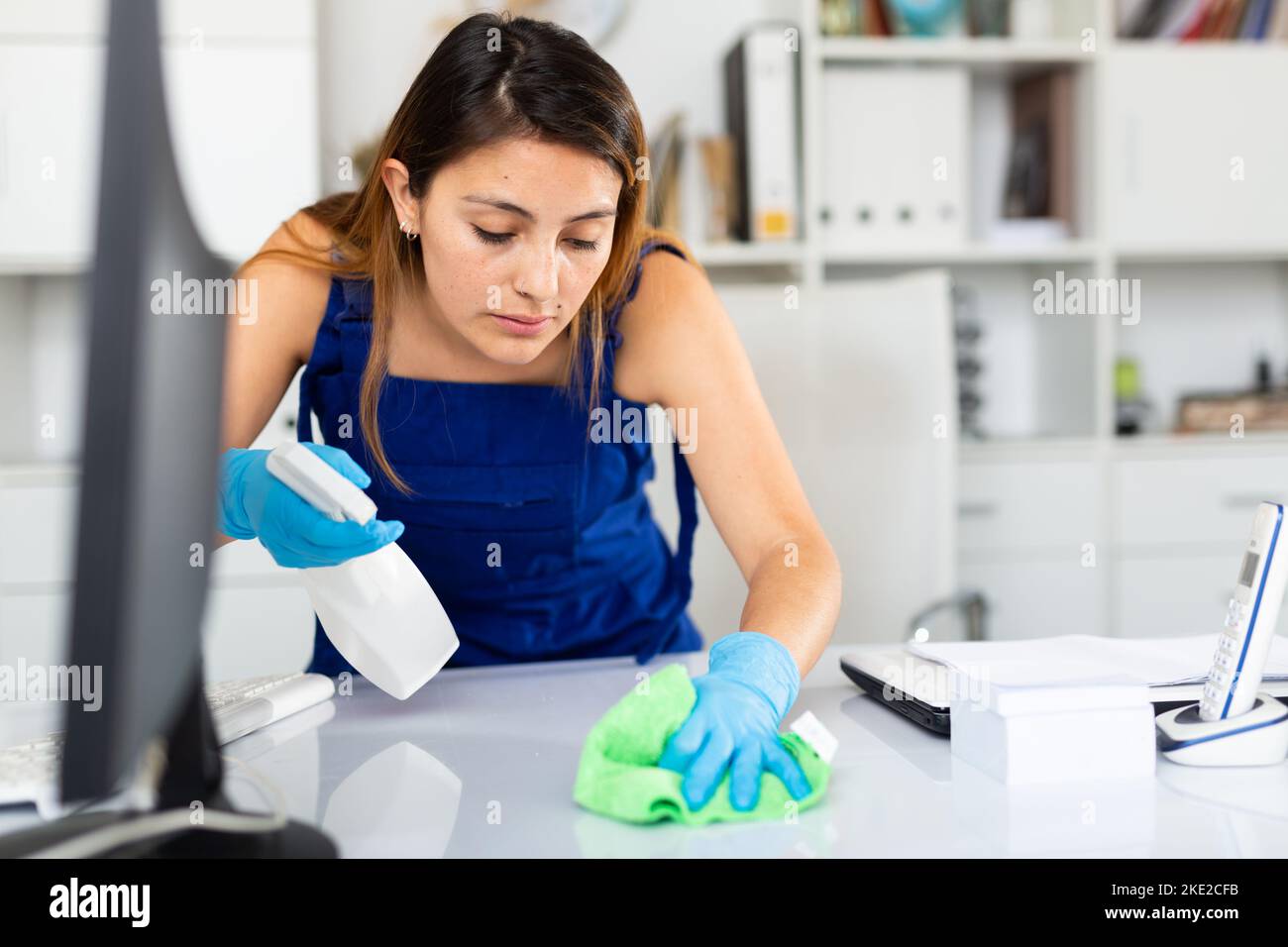 Woman cleaning desk in office Stock Photo - Alamy
