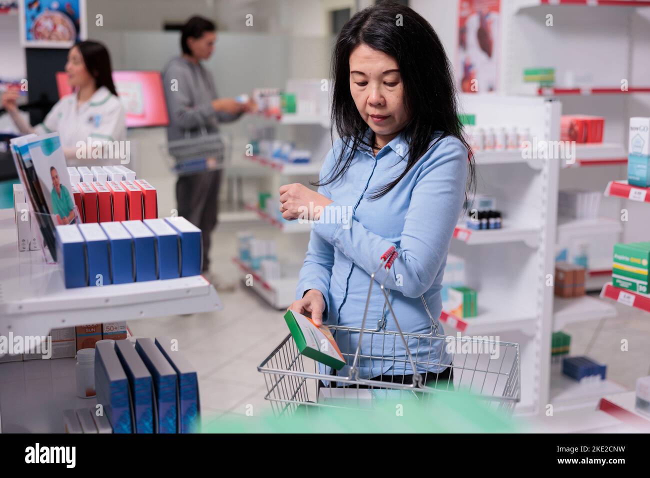 Asian client taking box of vitamins from pharmacy shelves, buying ...