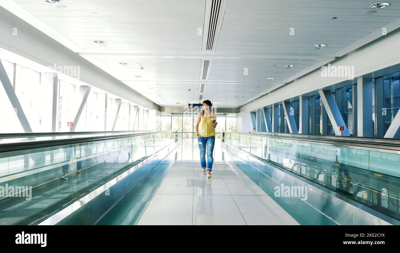 Woman walking between Automatic walkways, in subway crossing, using her ...