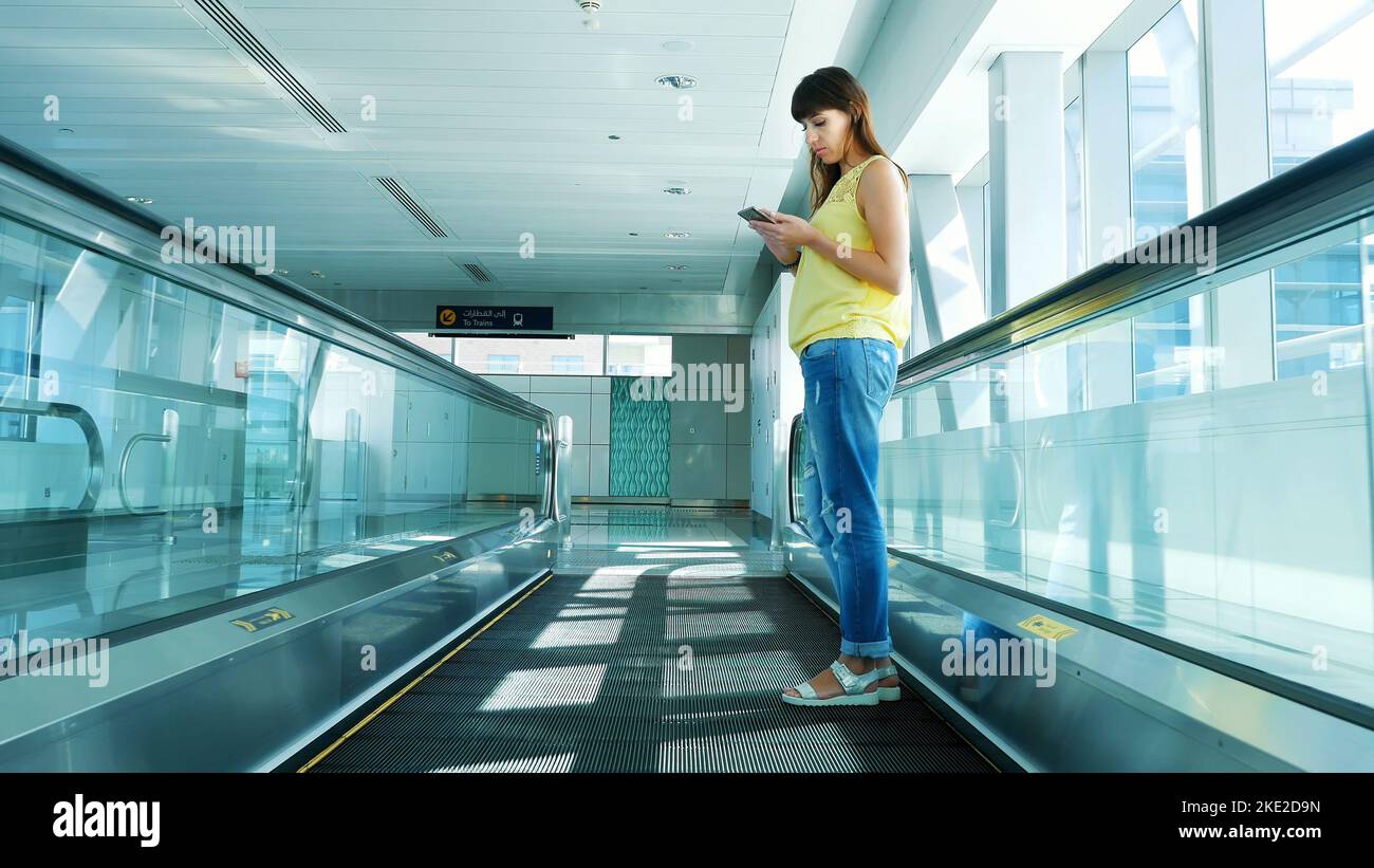 Woman standing on Automatic walkway, stairs in subway crossing, using ...