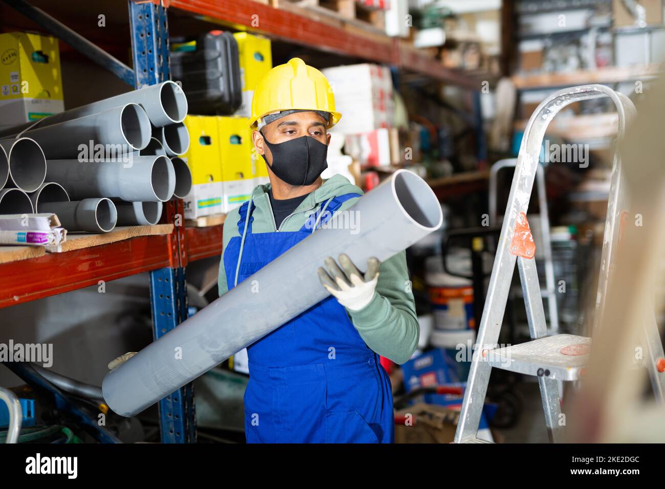 Foreman in protective mask looking for PVC pipes in building ...