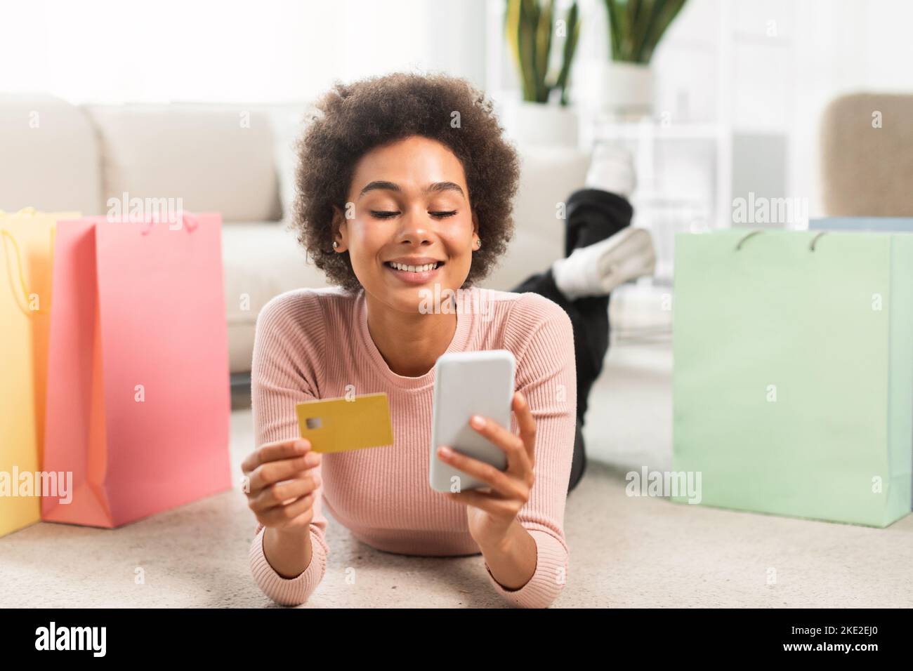 Smiling young african american woman with many packages with purchases ...