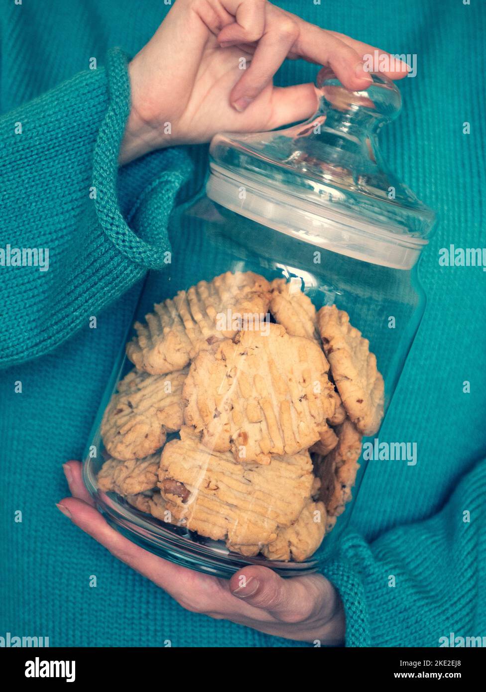 Young woman in warm turquois sweater is keeping the glass jar with ...