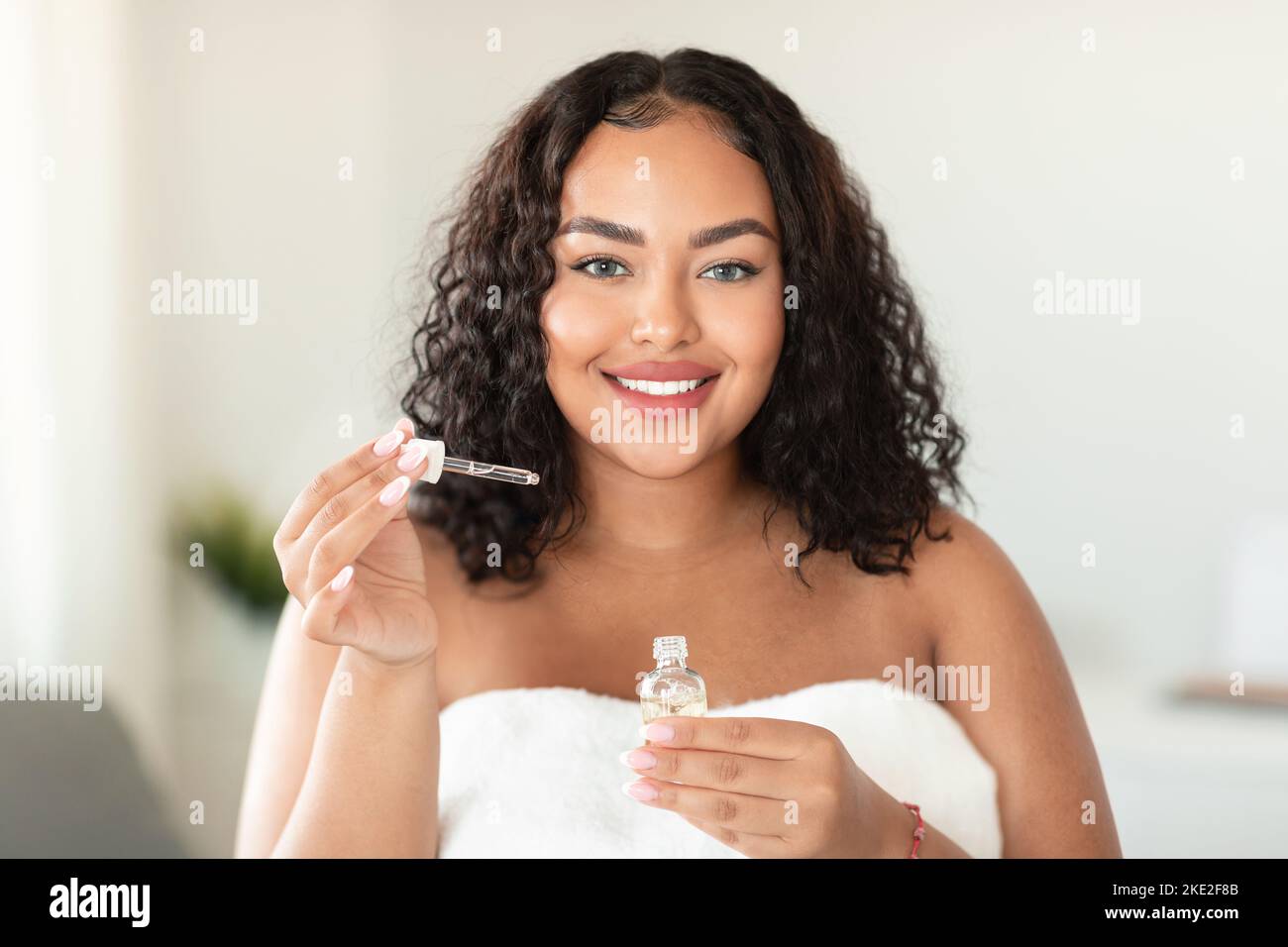 Skin care cosmetics. Beautiful black plus size lady holding bottle with ...