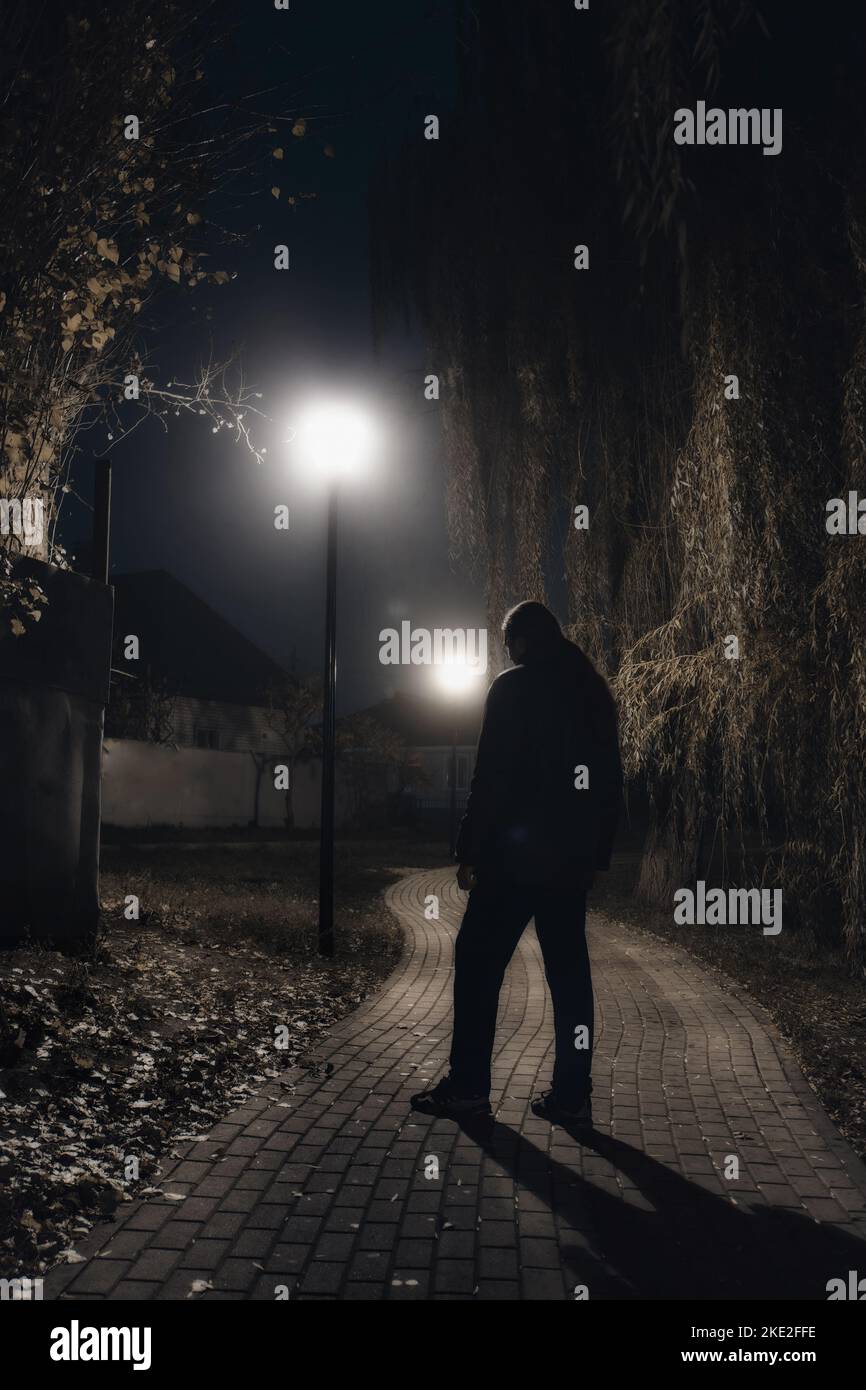 Sad man alone walking along the alley in night foggy park Stock Photo ...