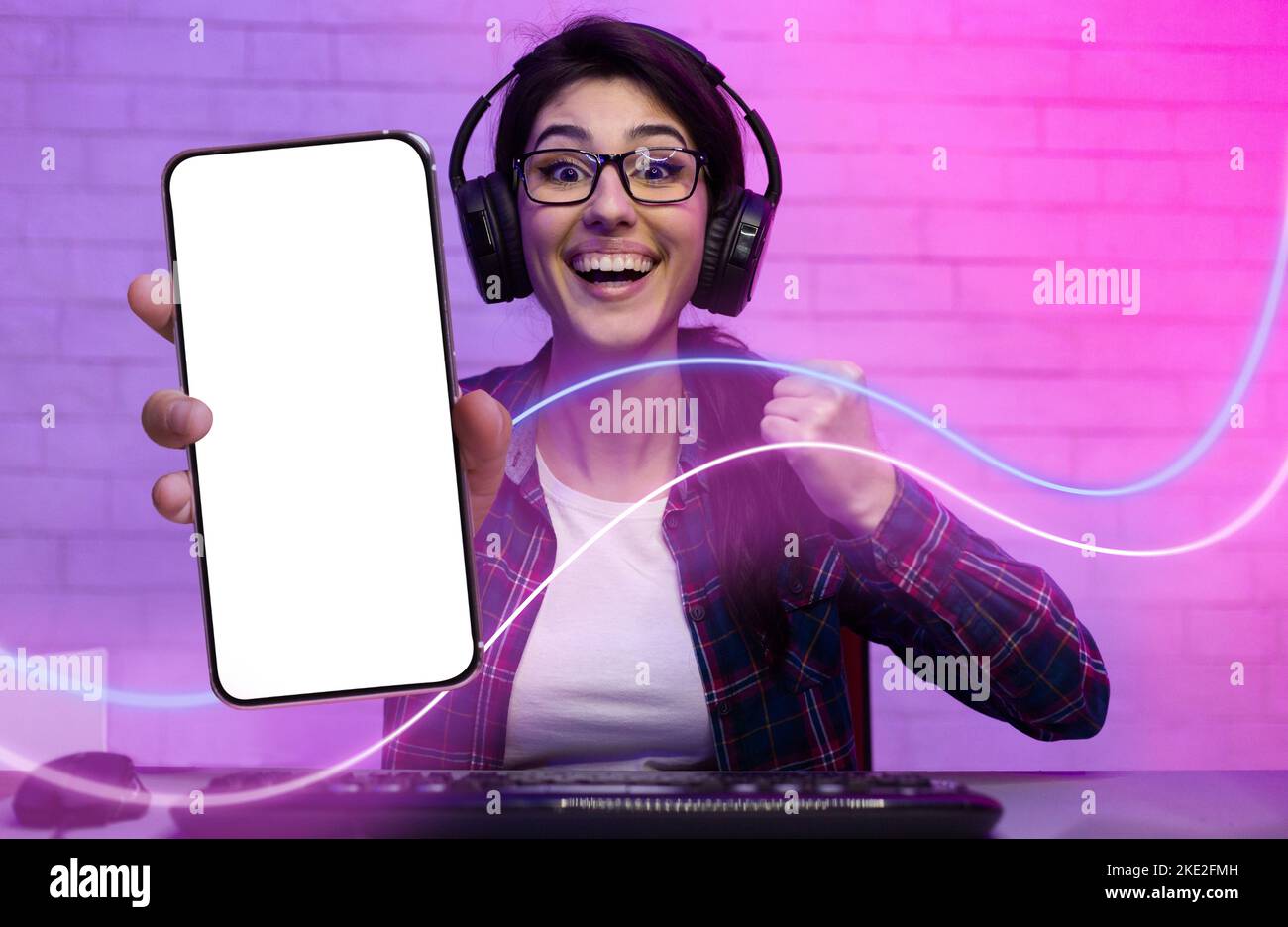 pretty millennial lady playing computer games, showing smartphone Stock ...