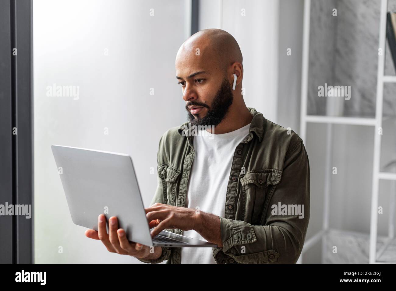 Mature latin male freelancer using laptop computer and wearing earbuds ...