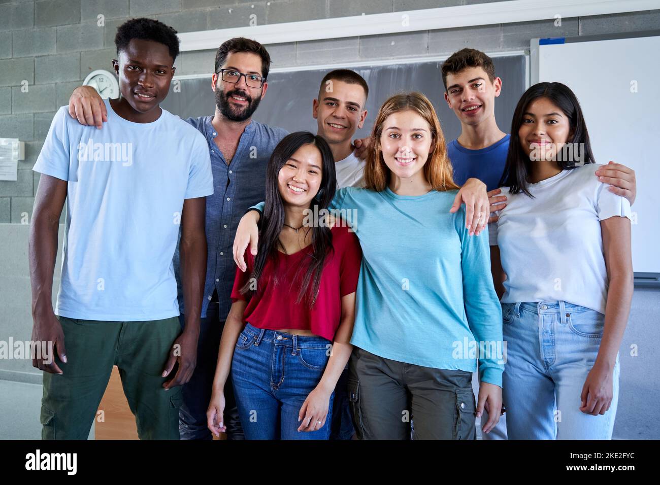 cheerful group of mixed race students standing at classroom with their ...