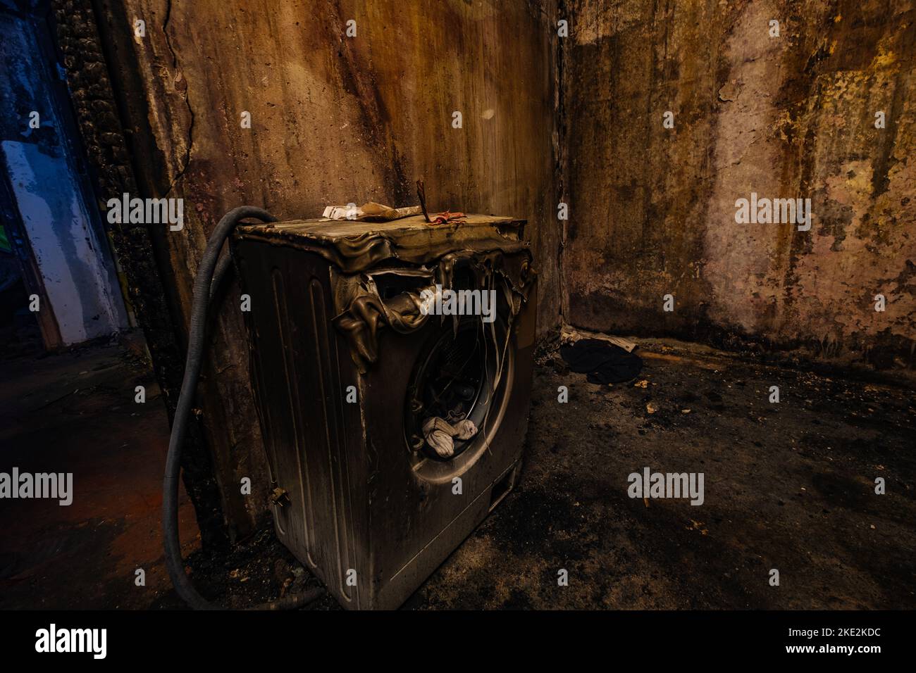 Burnt house interior. Fused remains of furniture and washing machine ...