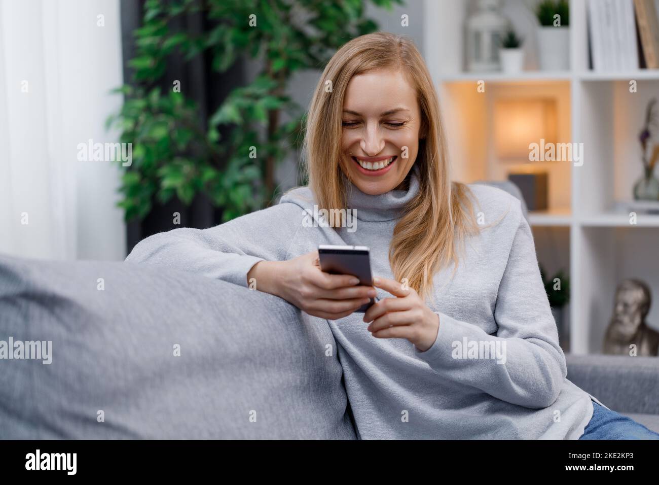 Using smartphone on couch woman hi-res stock photography and images - Alamy