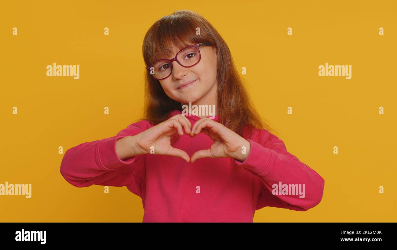 I love you. Smiling young preteen child girl kid makes heart gesture ...