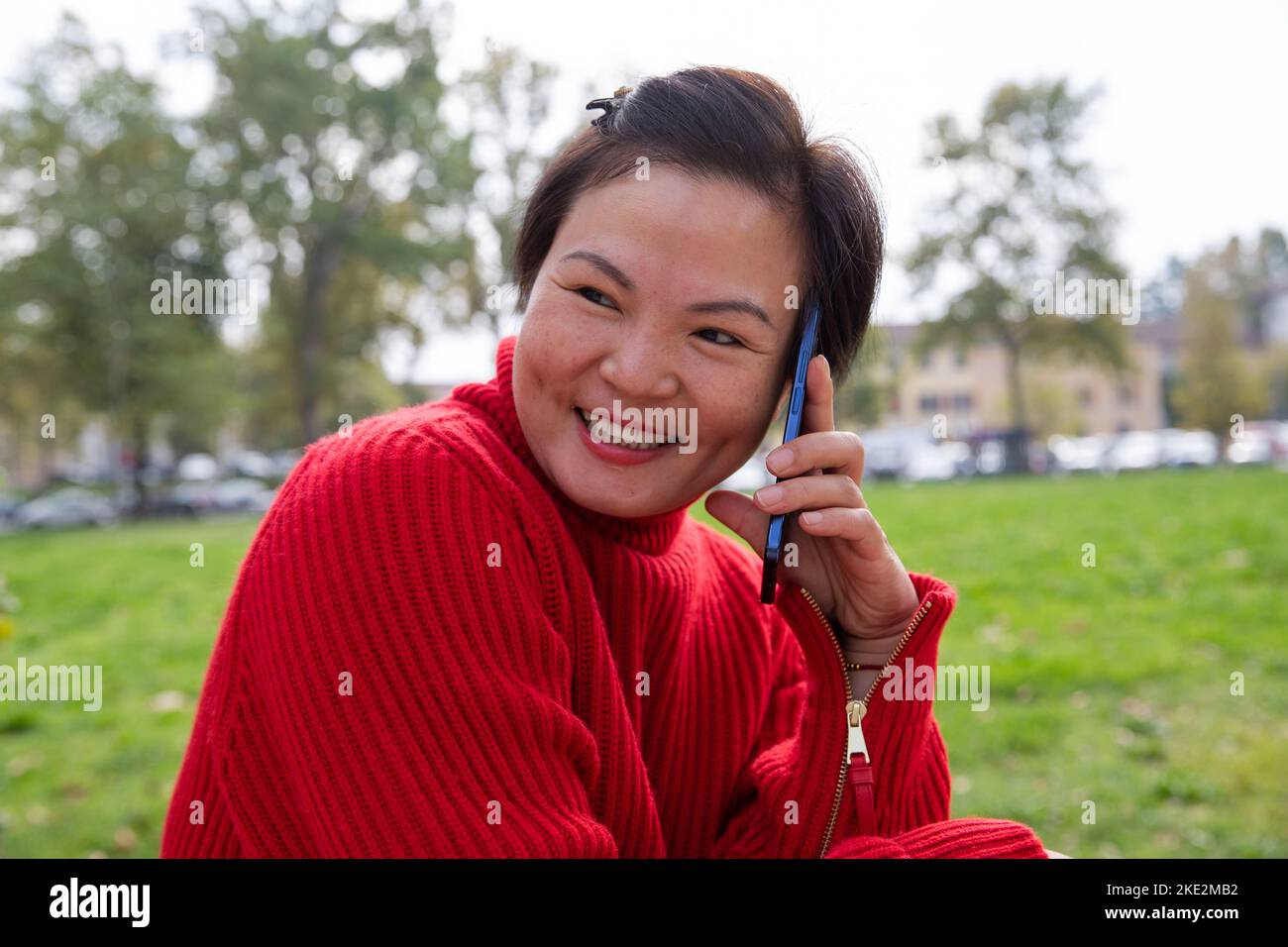 Smiling dimpled beautiful chinese woman talking at the cellphone at the ...