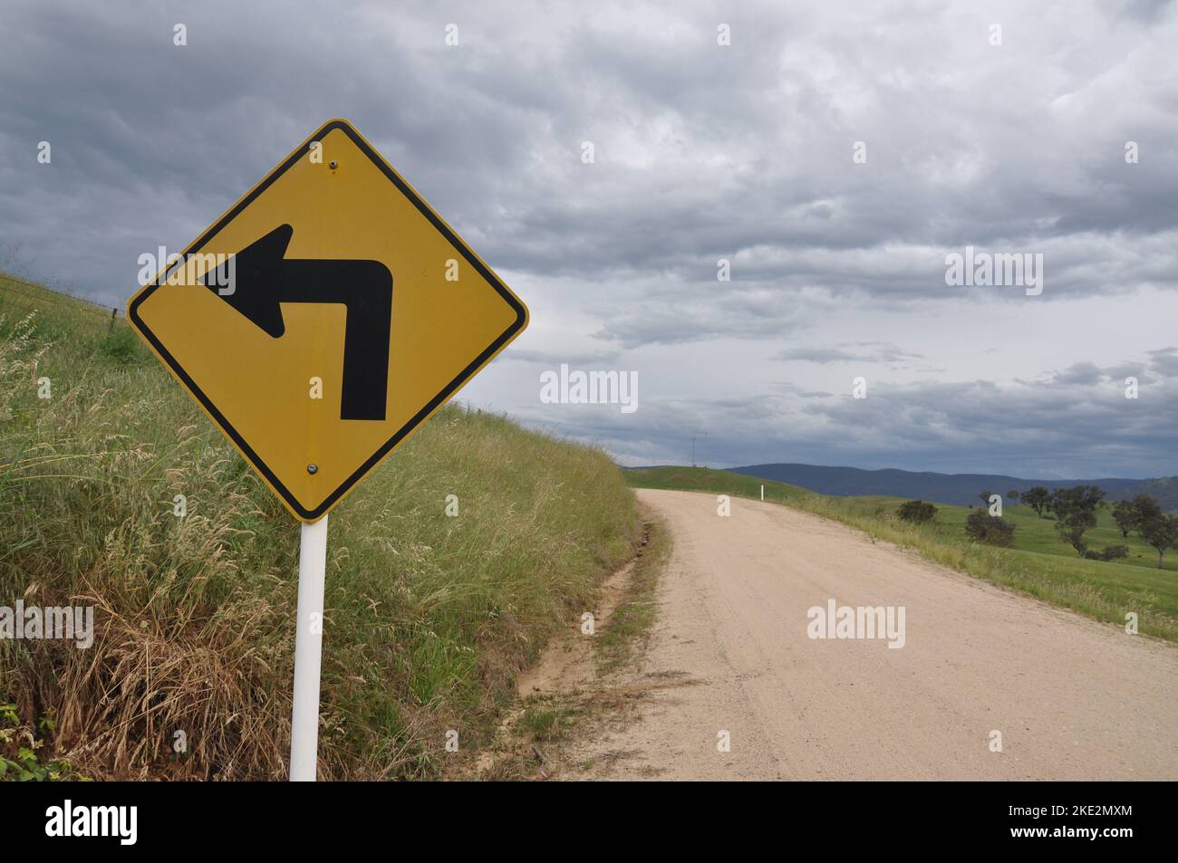 Dirt road with left arrow sign Stock Photo - Alamy