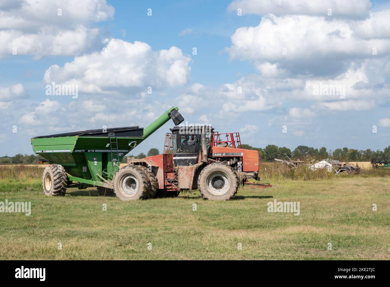 A farmer operating a John Deere combine harvesting rice in a rice field ...