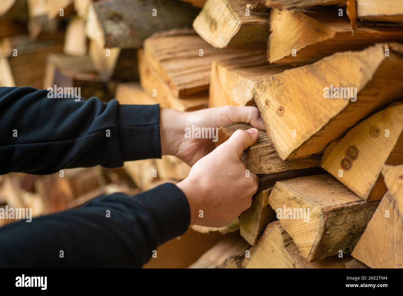 Heating season. Firewood.hands pulling a log from a woodshed. Male ...