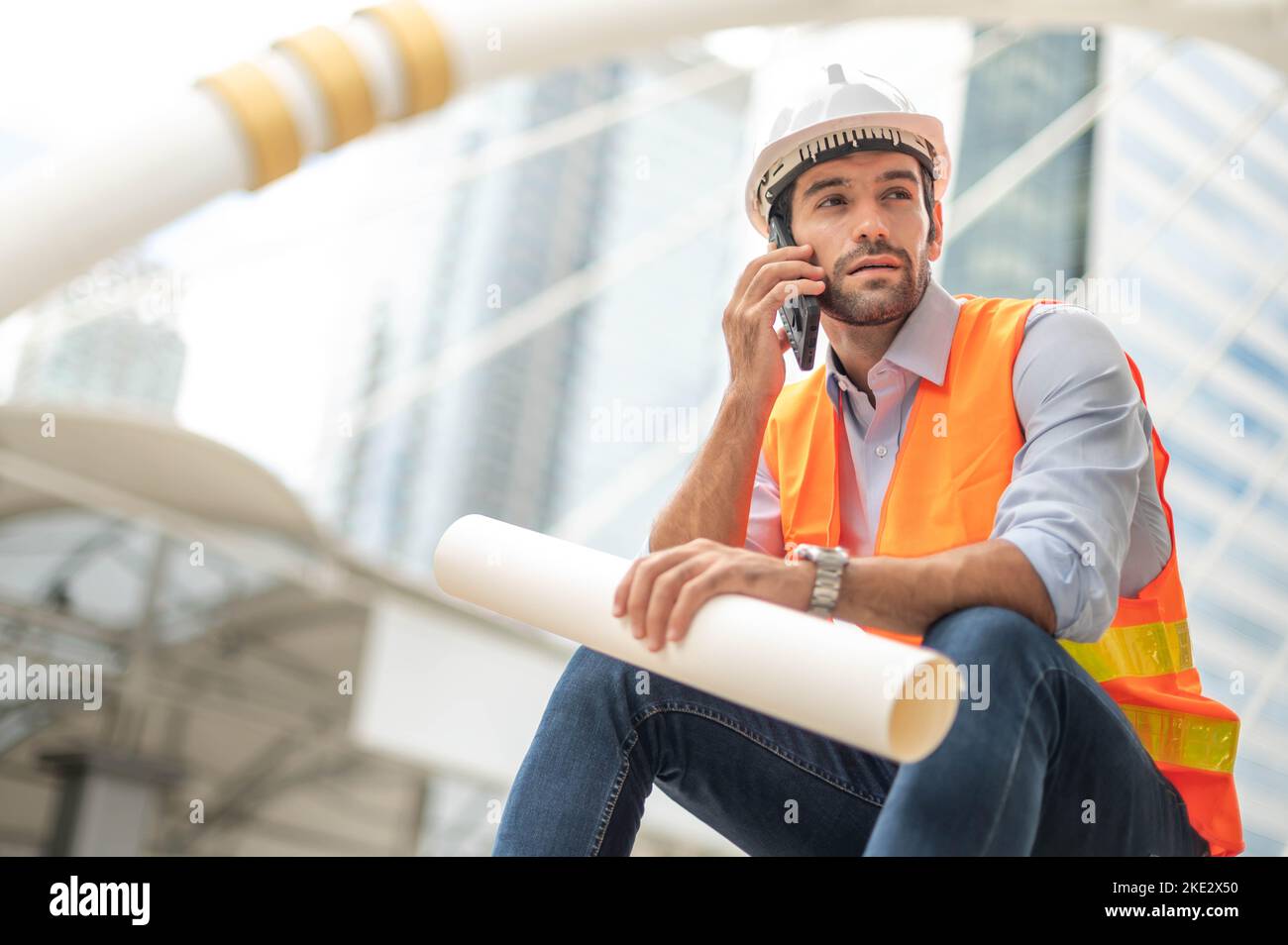 Caucasian man engineers use a smartphone for talking, wearing an orange ...