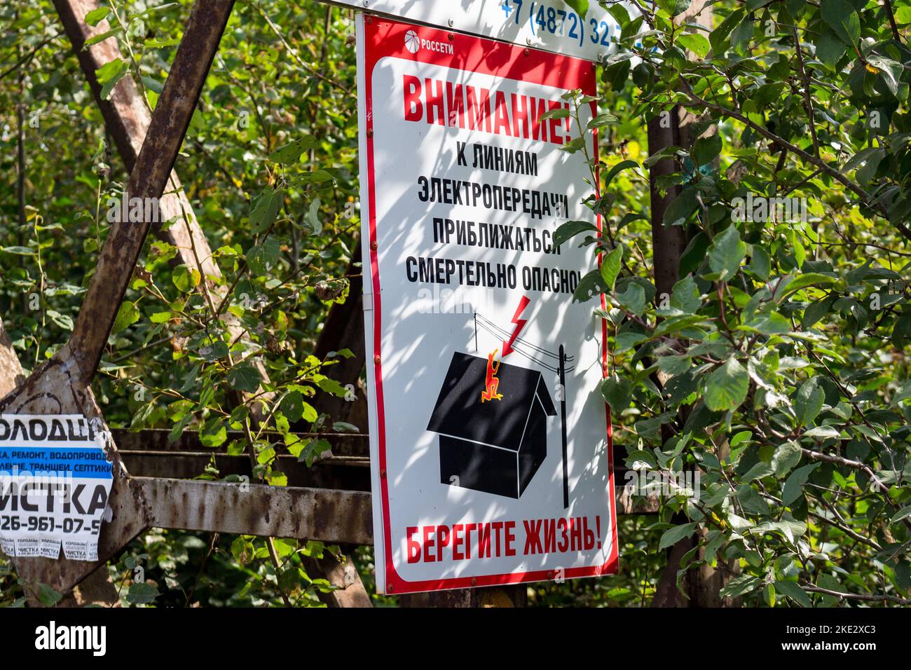 Warning sign under high voltage power line pylon - Attention! It is ...