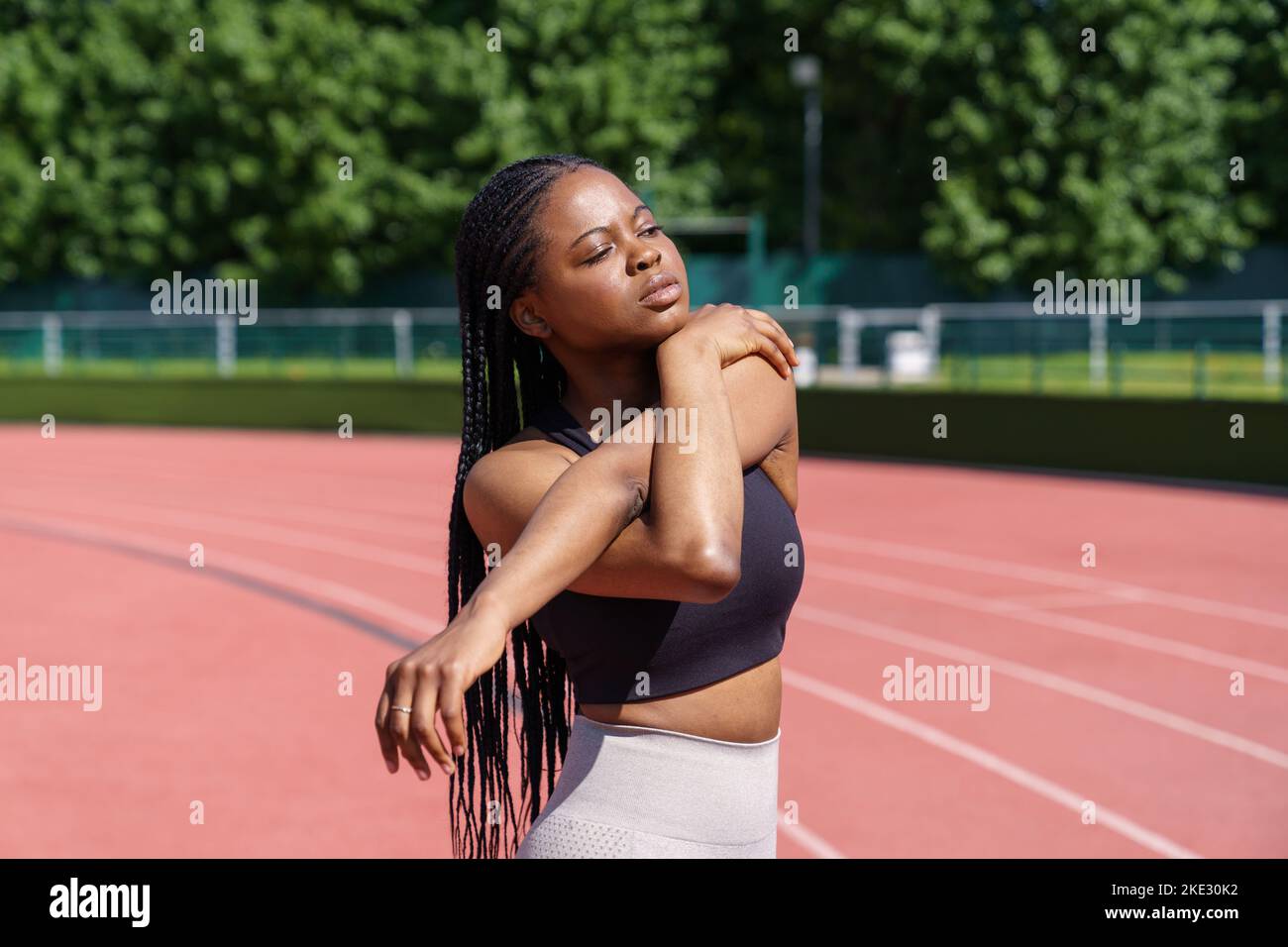 Black young woman with long braids stretches hands and shoulders ...