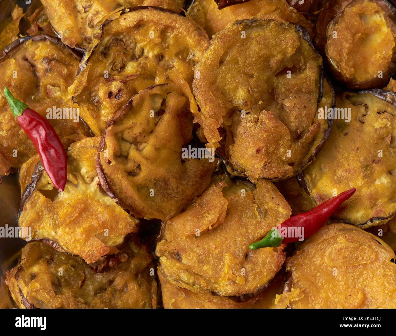 close-up of fried eggplant with batter and red chilly peppers, golden ...