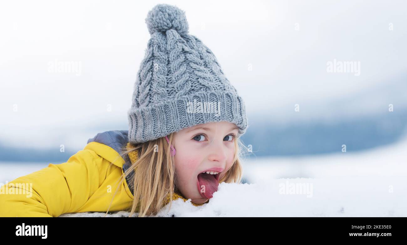 Winter girl eating snow outdoor. Kids cold and flu concept. Kid lick ...