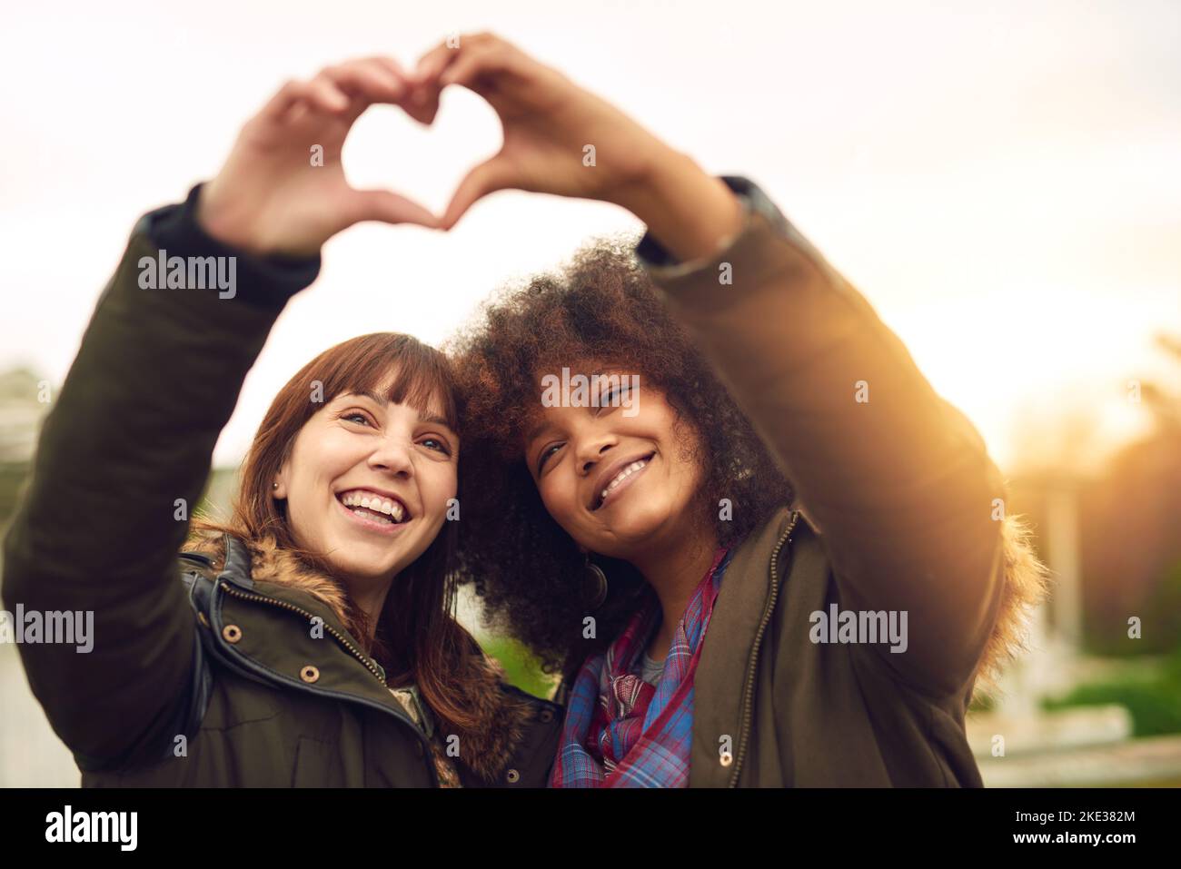 Were sisters at heart. two friends making a heart shape with their ...